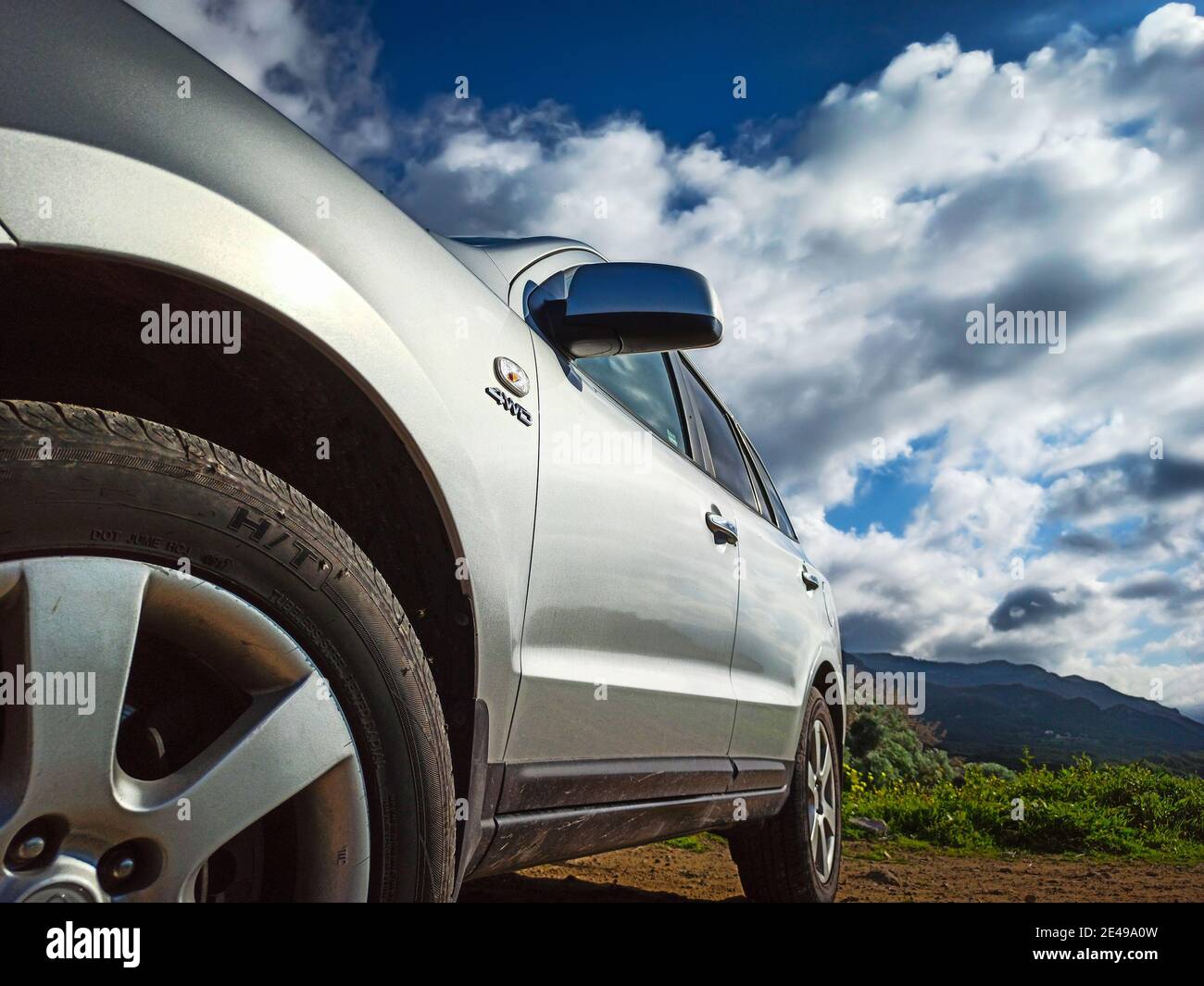 Modern SUV parked in the countryside under a blue sky with clouds seen ...