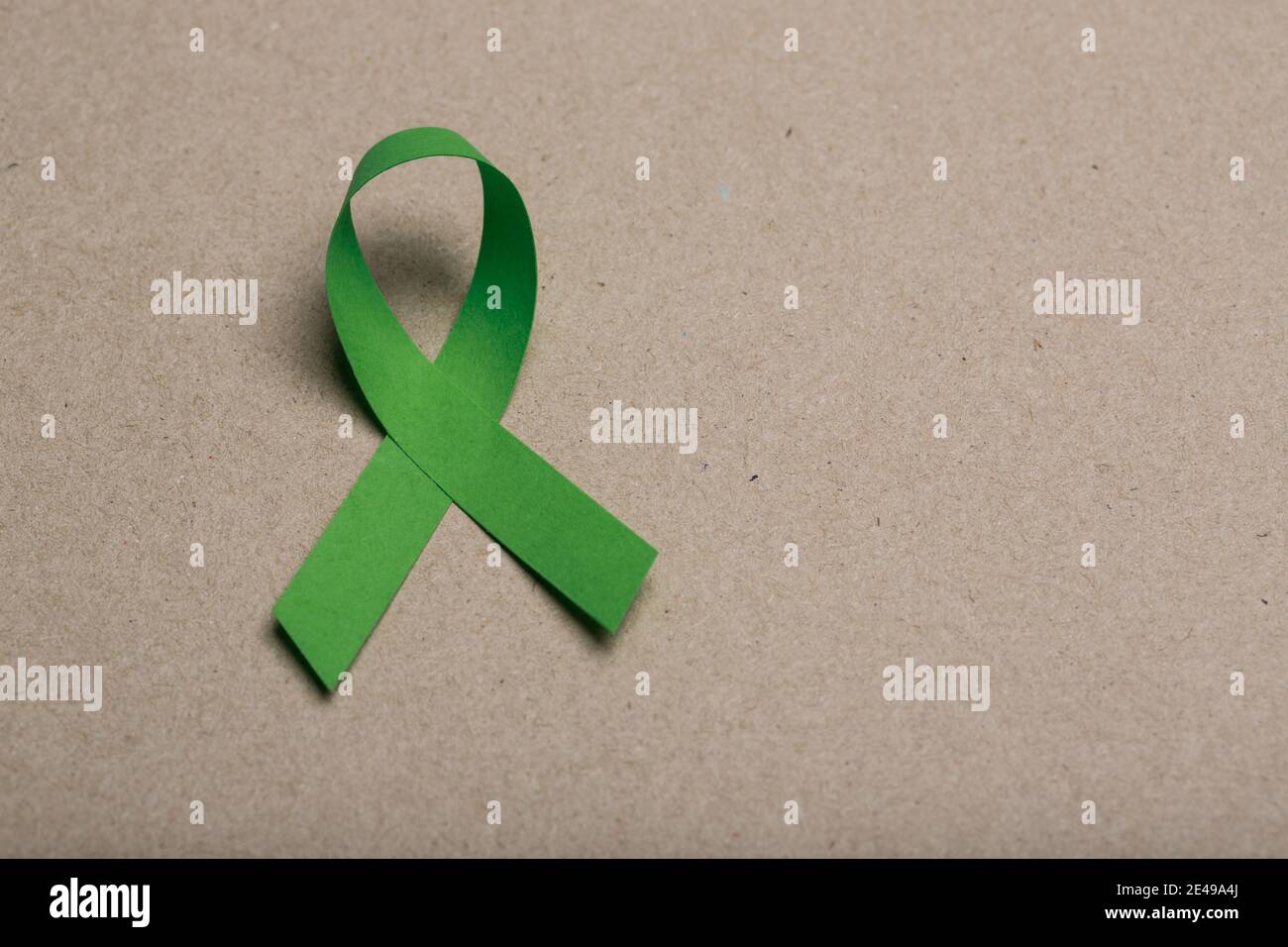 Green handmade awareness paper ribbon on cardboard background Stock ...