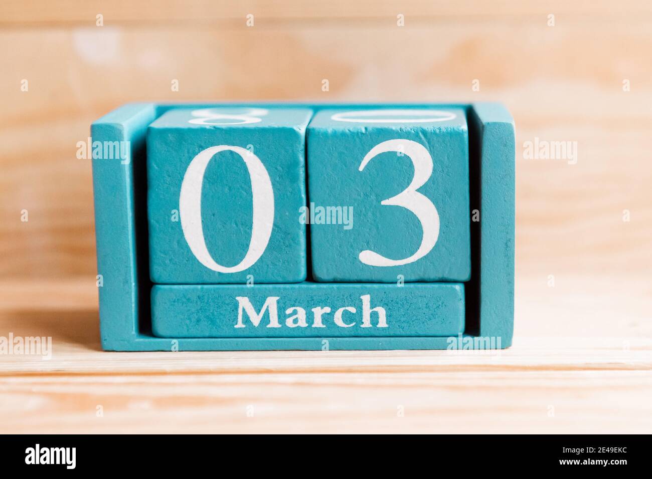 March 3. Blue cube calendar with month and date on wooden background ...