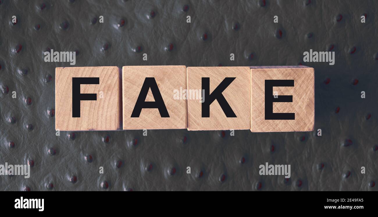 FAKE word written in wooden blocks on red leather. Fake or real news ...