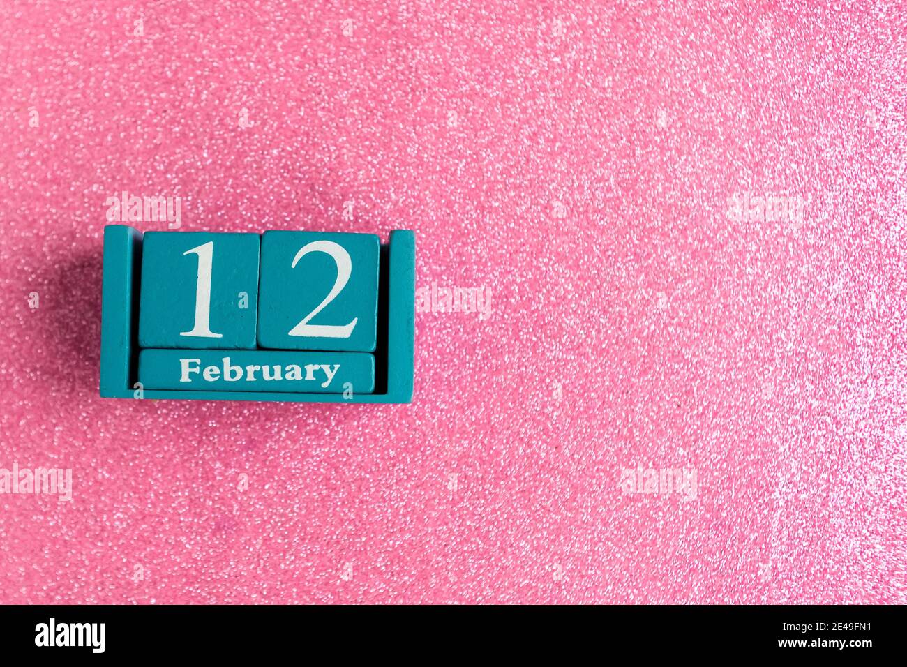 February 12. Blue cube calendar with month and date on pink glitter ...