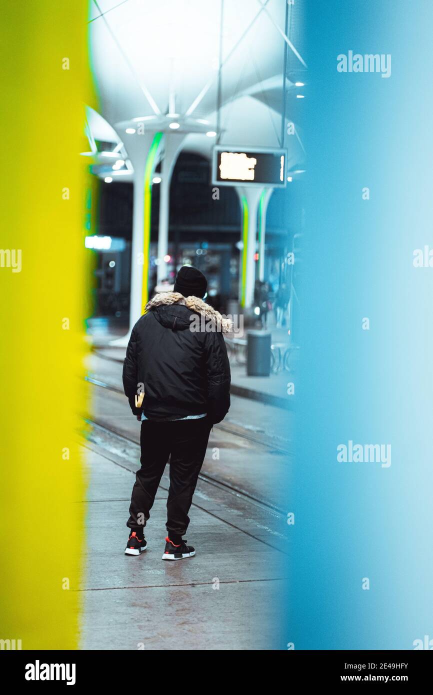 Back view of a male wearing a black winter jacket and waiting in the ...