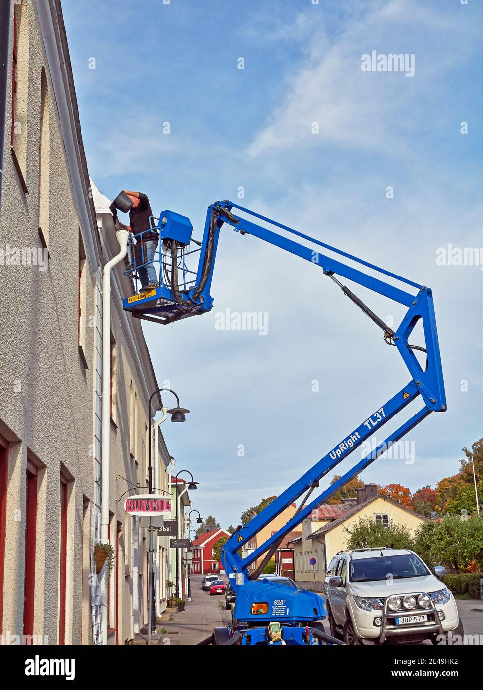 Workman in a hydraulic man lifting platform basket crane outside an old ...