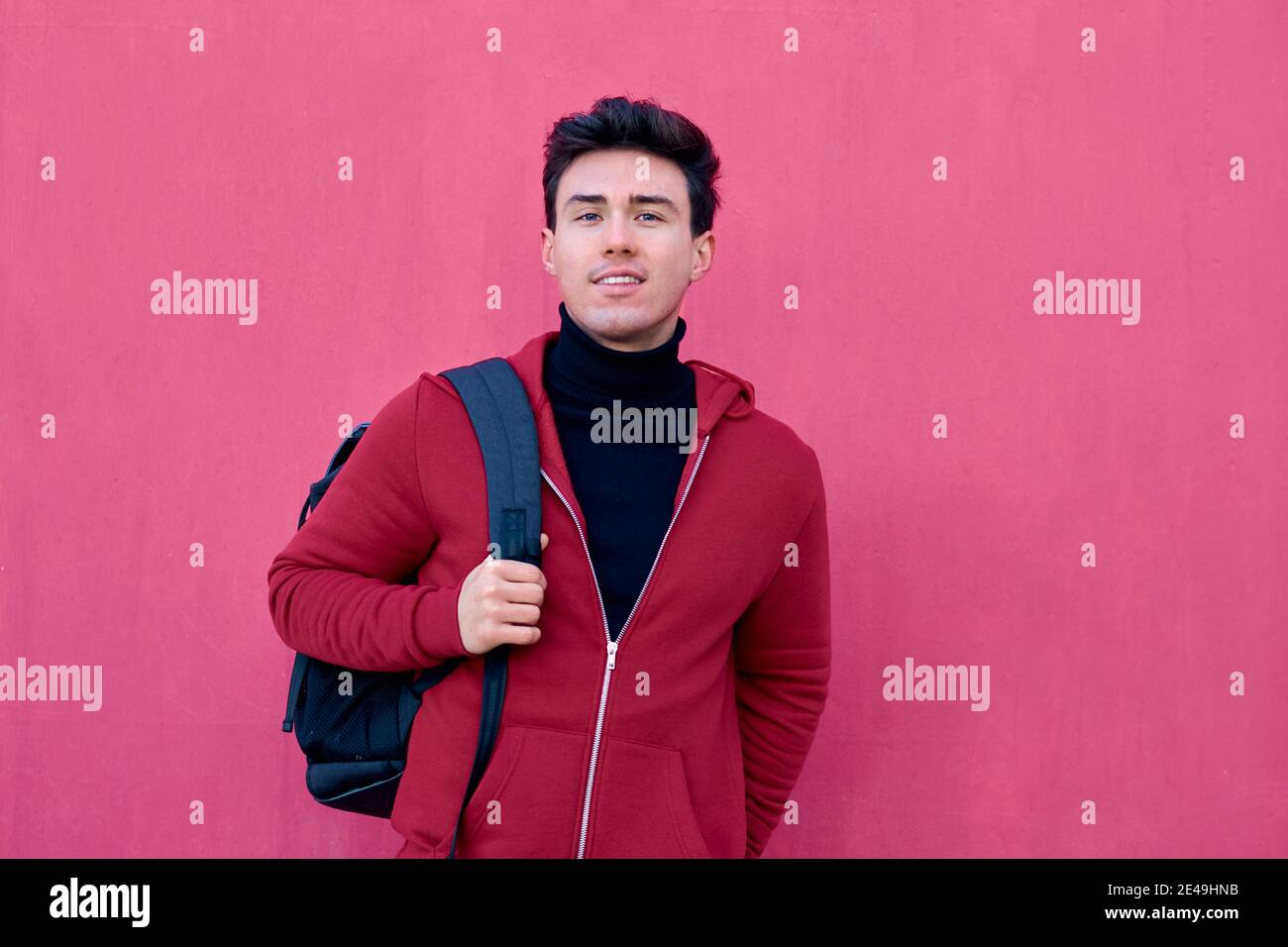 Handsome student man poses with a backpack on a pink background Stock ...