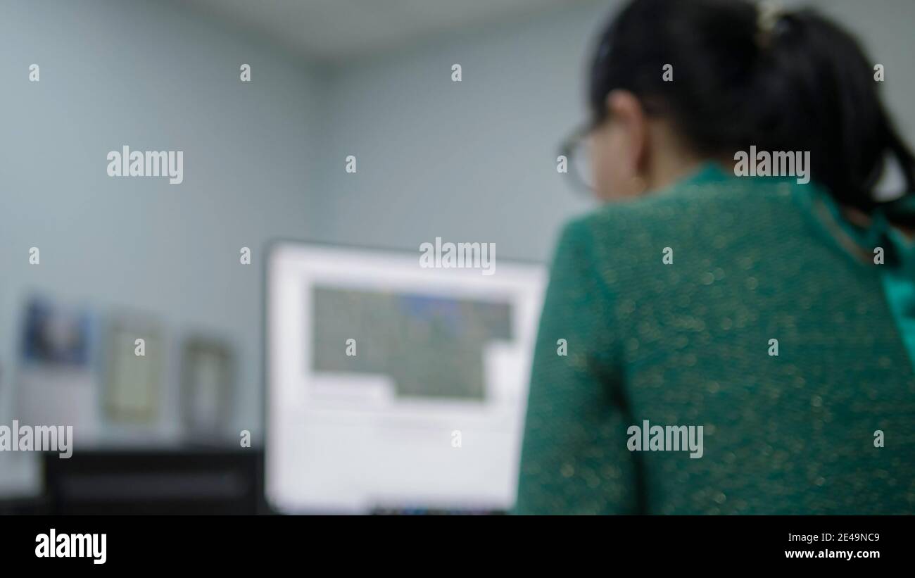 Office worker looks at the monitor, blurred background pictures of the ...