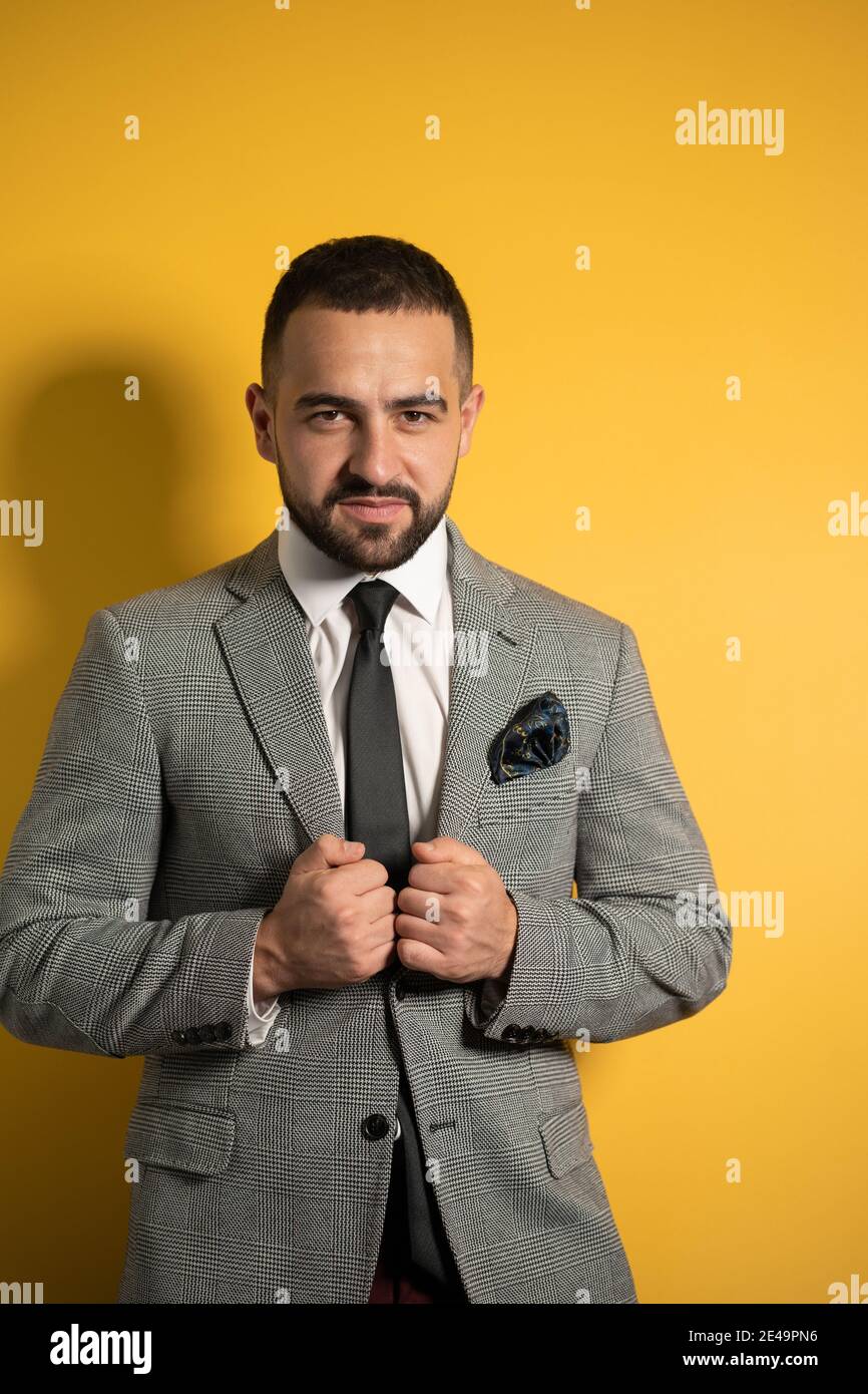 Holding jacket handsome slightly smiling young businessman wearing grey ...