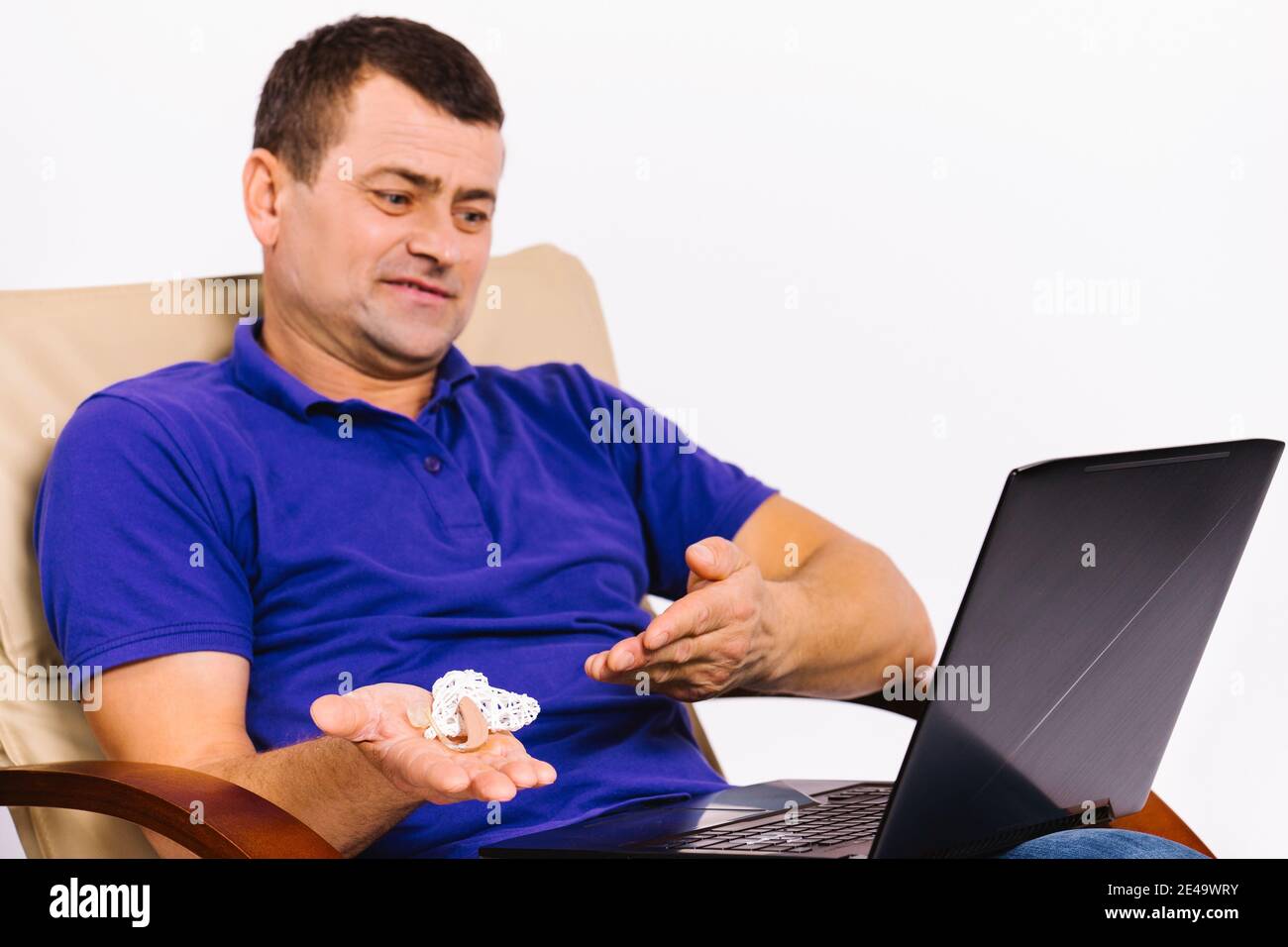 Caucasian deaf man with hearing impairment holds a hearing aid in his ...