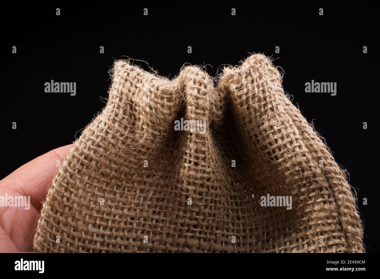 Hand holding a coarse burlap sack in the black background Stock Photo ...