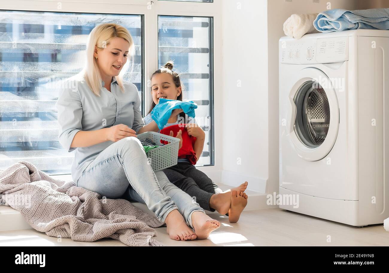 family mother and child girl little helper in laundry room near washing ...
