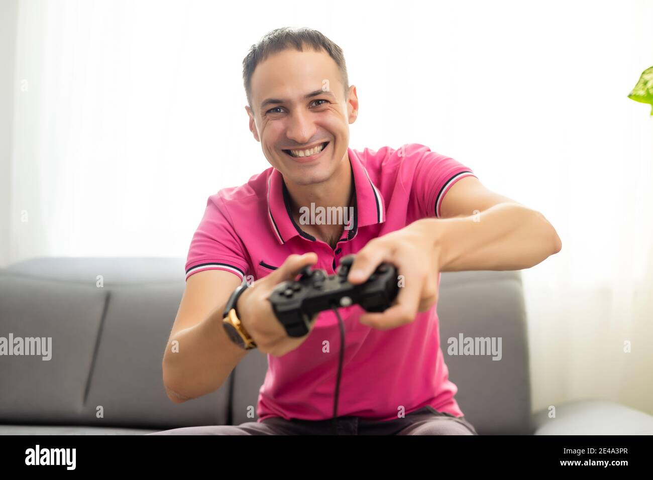 young excited man at home sitting on living room sofa playing video ...