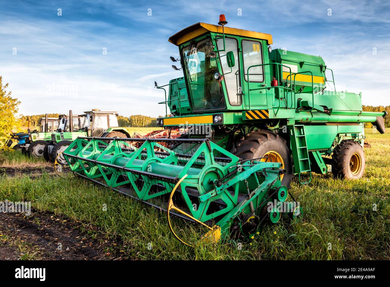 The modern combine harvester and wheeled agricultural tractors on field ...