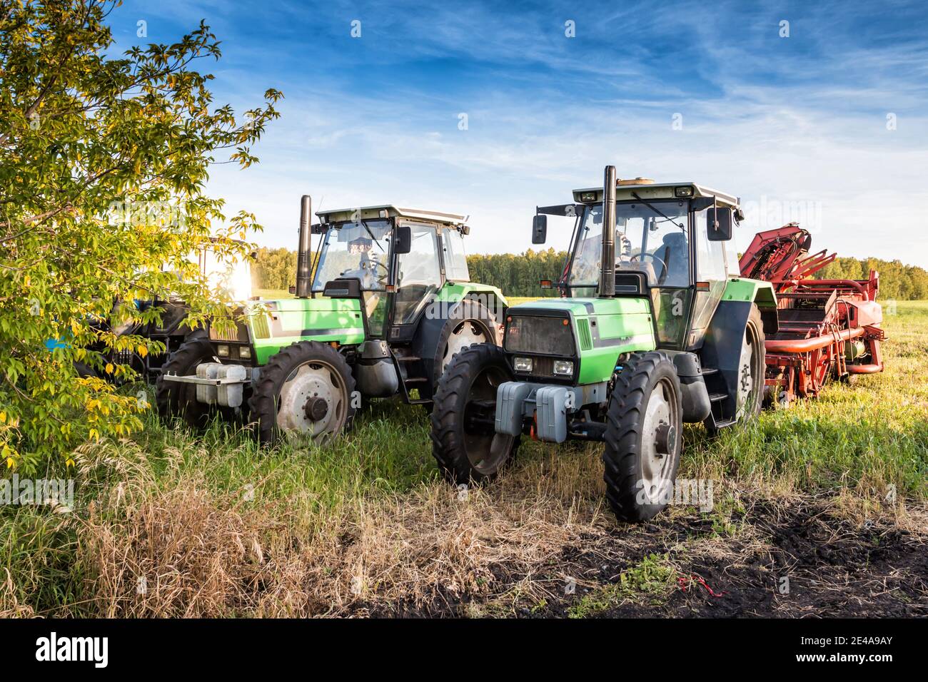 Modern wheeled agricultural tractors with harvesting equipment on an ...