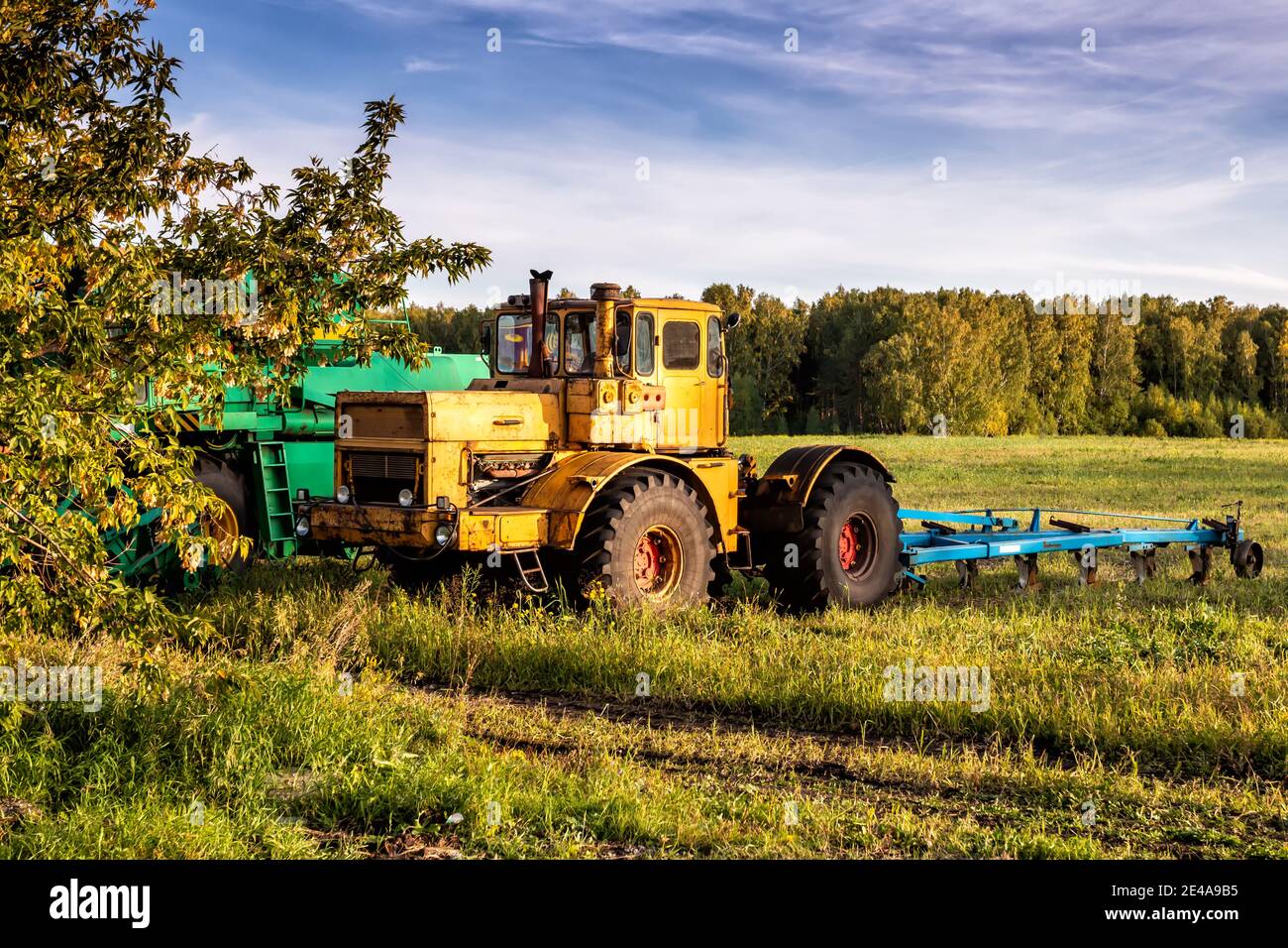 Wheeled agricultural tractor with harvesting equipment on an field ...