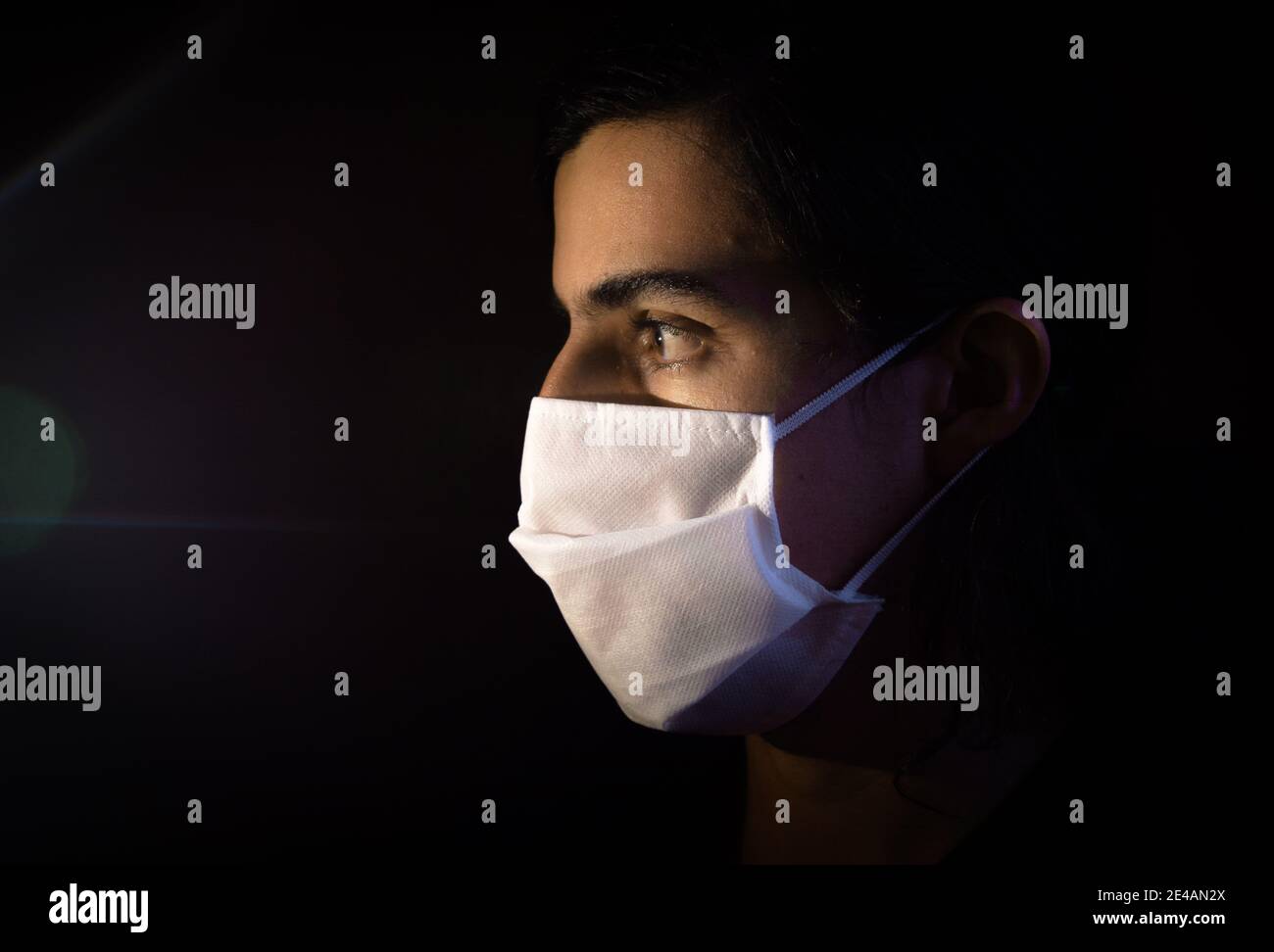 Profile portrait of a man with a disposable white face mask looking ...