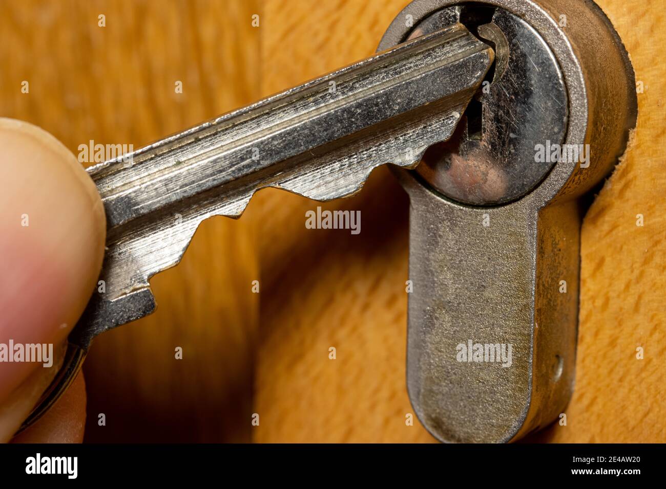 A hand puts the key in the keyhole. The key inserted in a wooden door ...