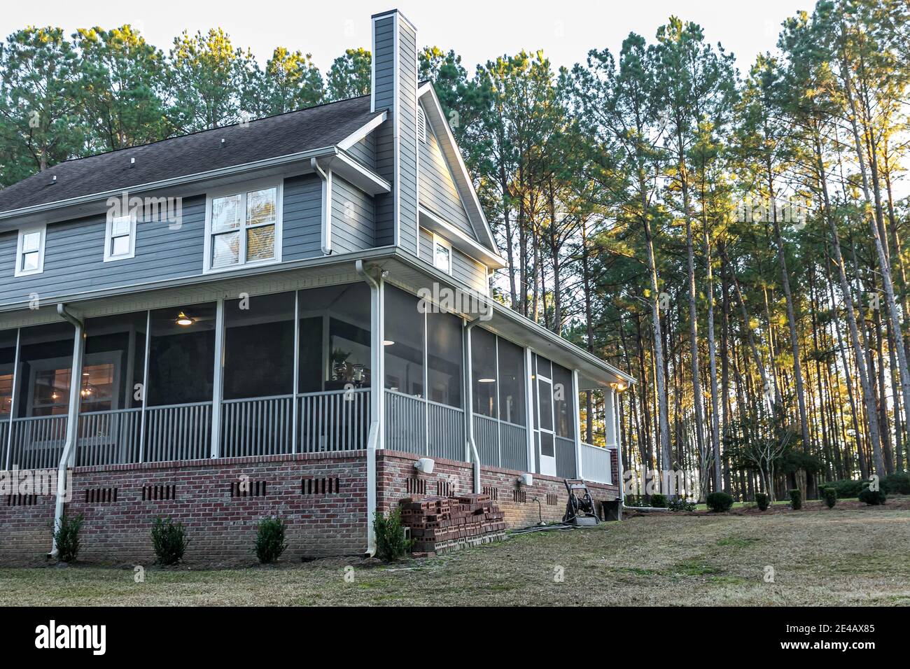 Rear side view of a large two story blue gray house with wood and vinyl ...