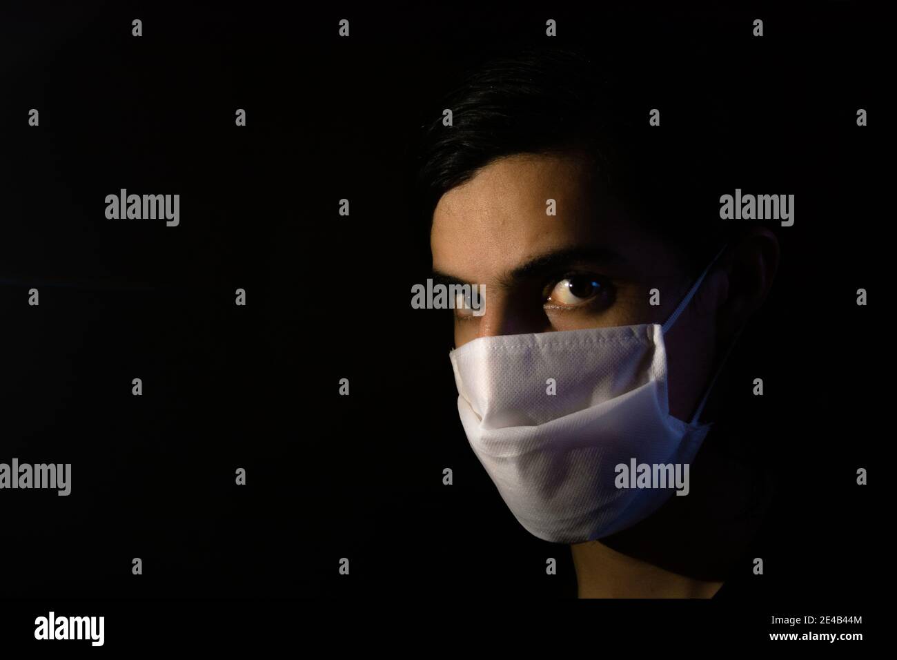 Portrait of a man with a disposable white face mask looking aside at ...