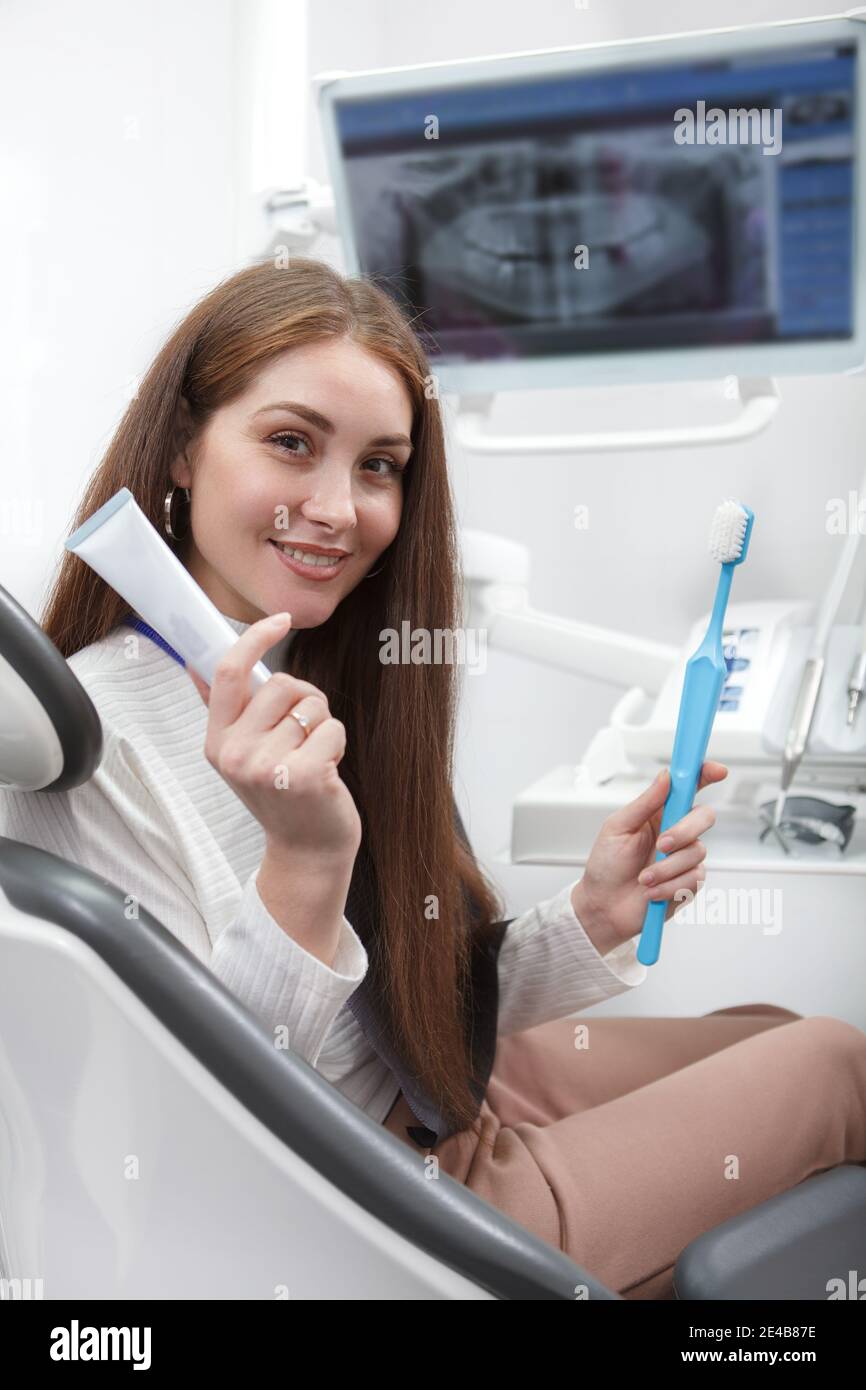 Vertical portrait of a cheerful woman holding toothbrush and toothpaste ...