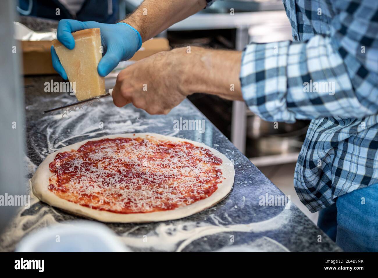 A man making a margherita pizza in a local pizza and gyros restaurant ...