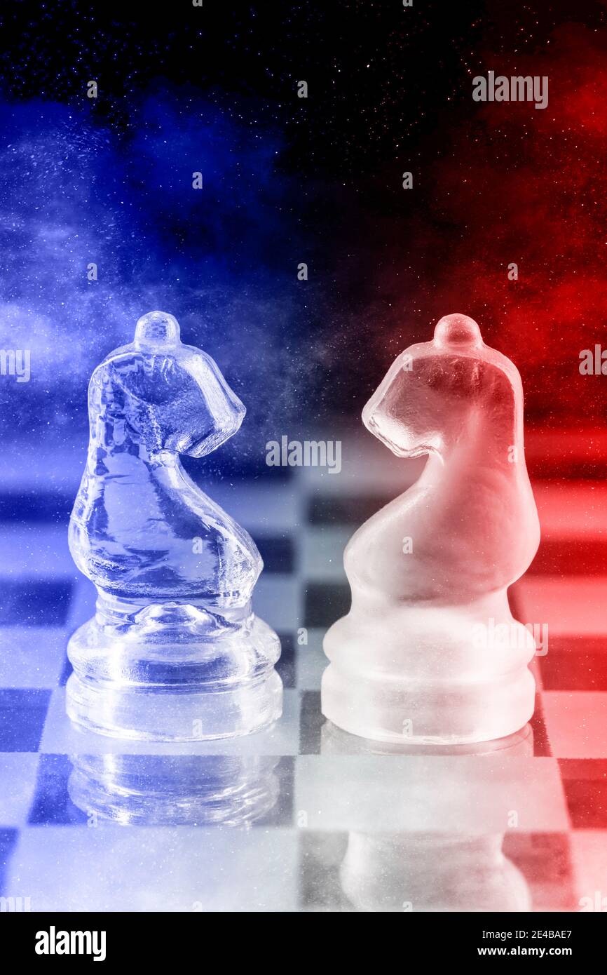Glass chess pieces with blue and red light on a glass chessboard with ...