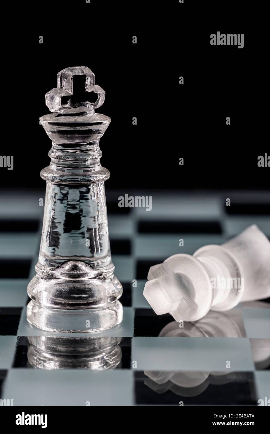 Glass chess pieces on a glass chessboard with reflection, on a black ...