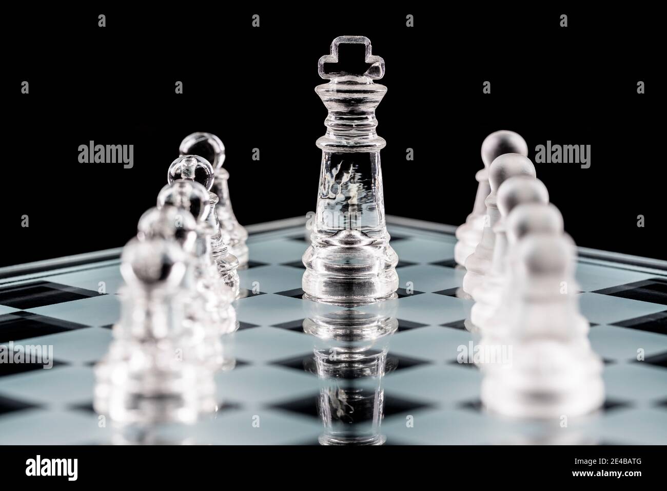 Glass chess pieces on a glass chessboard with reflection, on a black ...