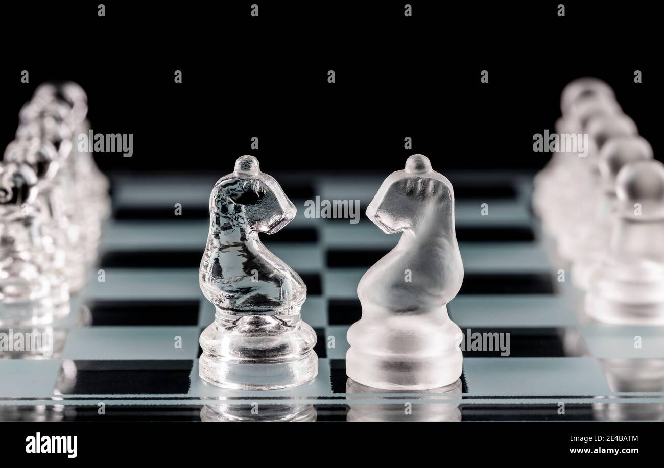 Glass chess pieces on a glass chessboard with reflection, on a black ...