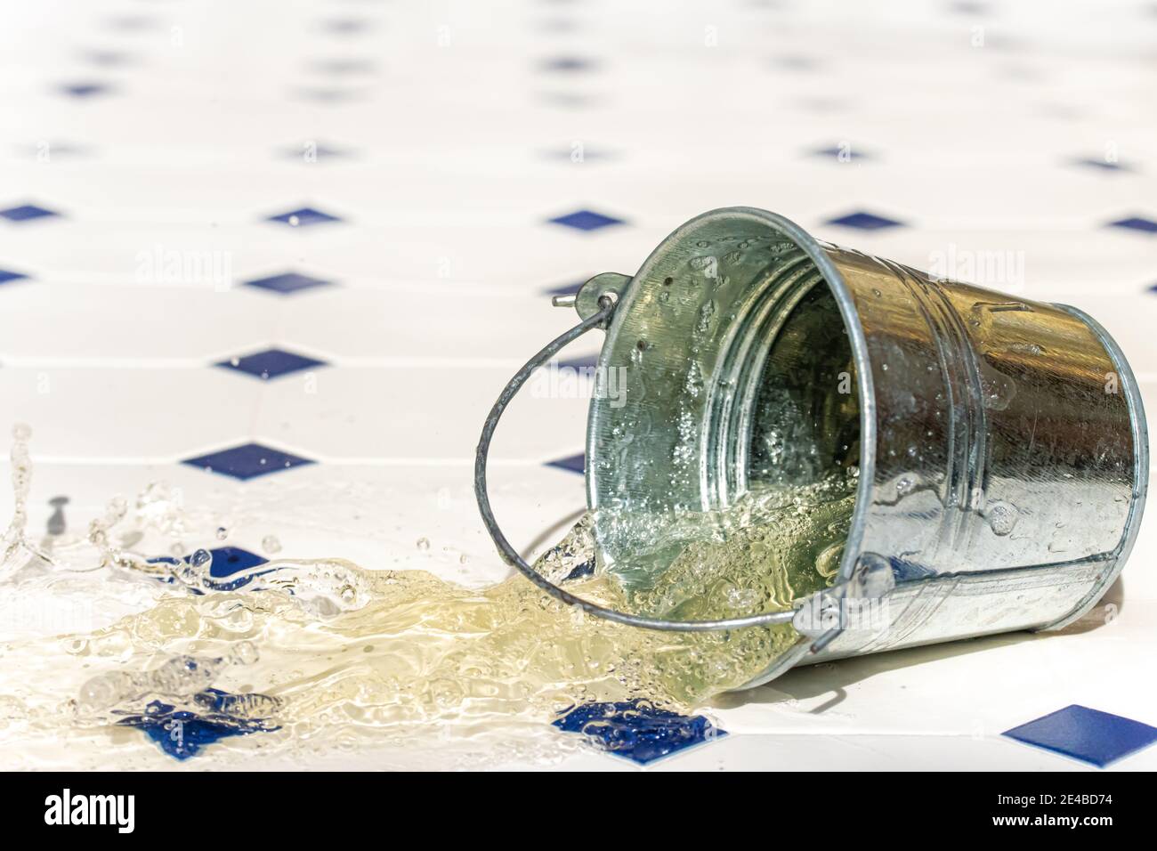 A metal bucket falls to the floor and splashes out the water with a ...