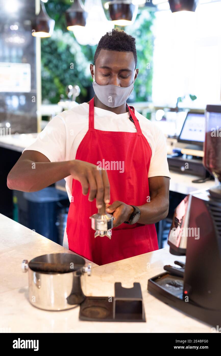 Portrait of african american male barista wearing face mask using ...