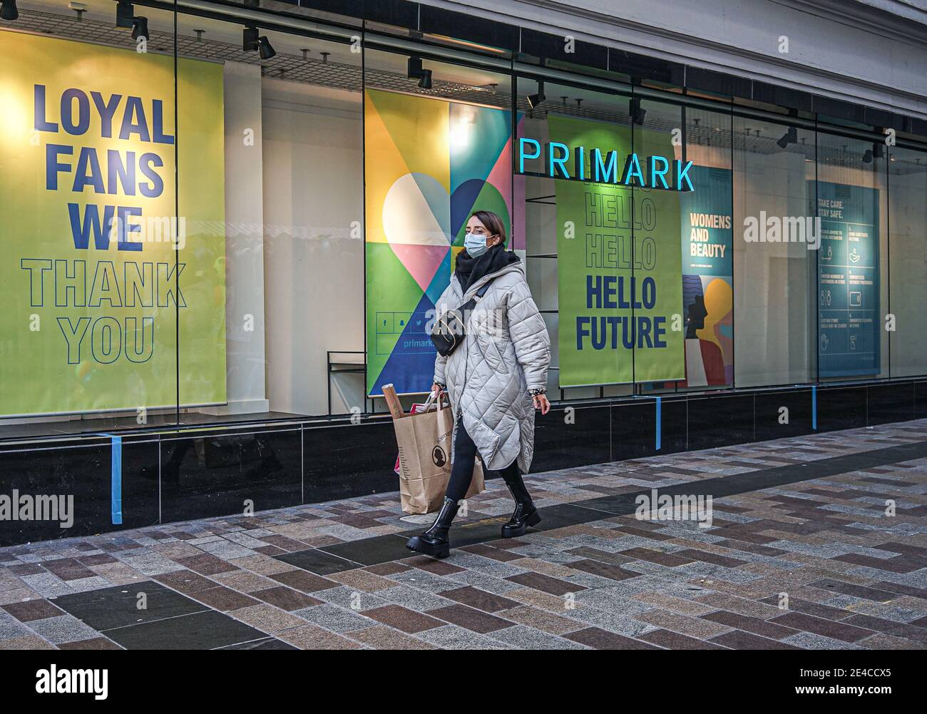 A shopper wearing a face mask walks past Primark fashion store. (Photo ...