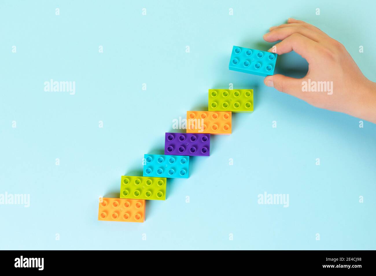 Man's hand making a ladder made of colorful building toy blocks ...