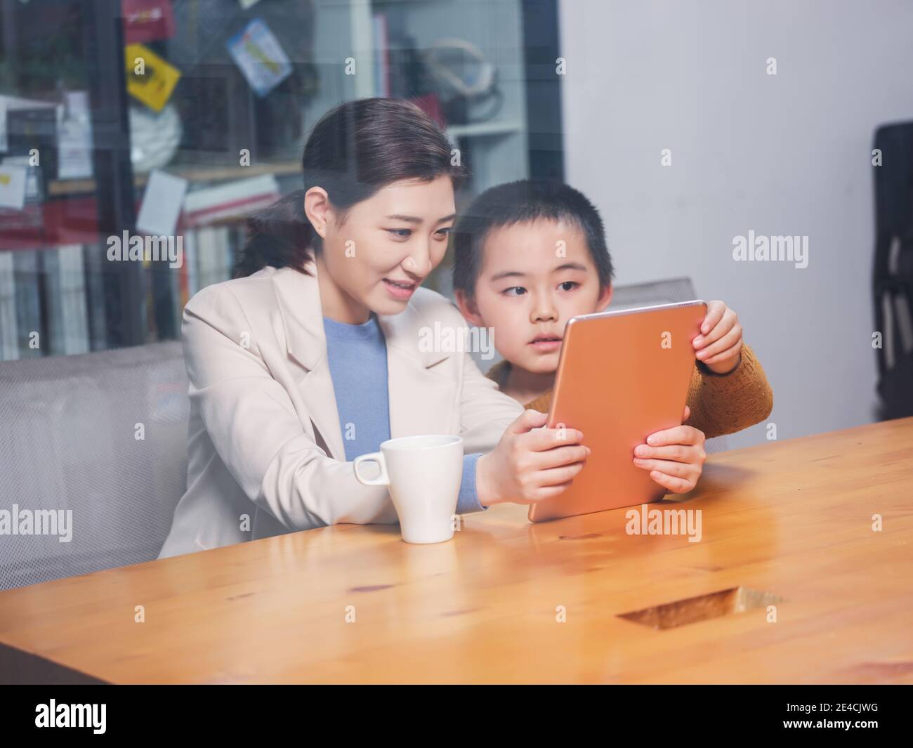 Mom and kids watch tablets smiling without looking at the lens Stock ...