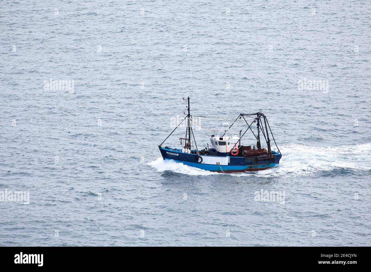 A fishing boat goes around the cliffs of Cap Frehel. Brittany, France ...