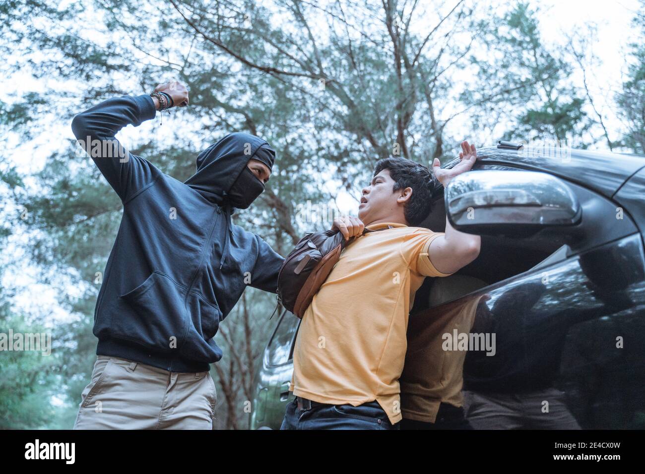 man driving the car is scare when a robber points a knife at him while ...