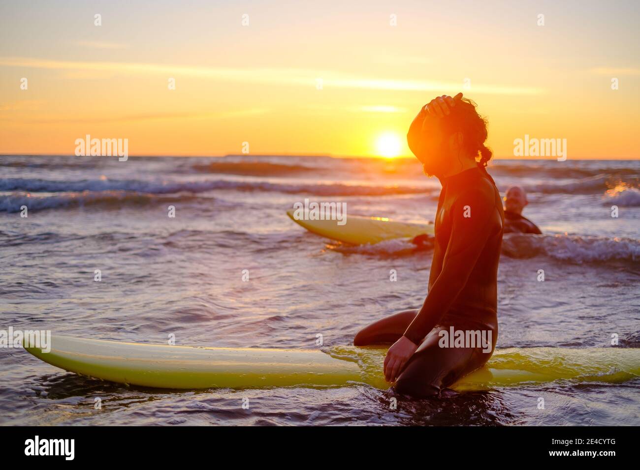 Surfer sitting on surfboard in sea Stock Photo - Alamy