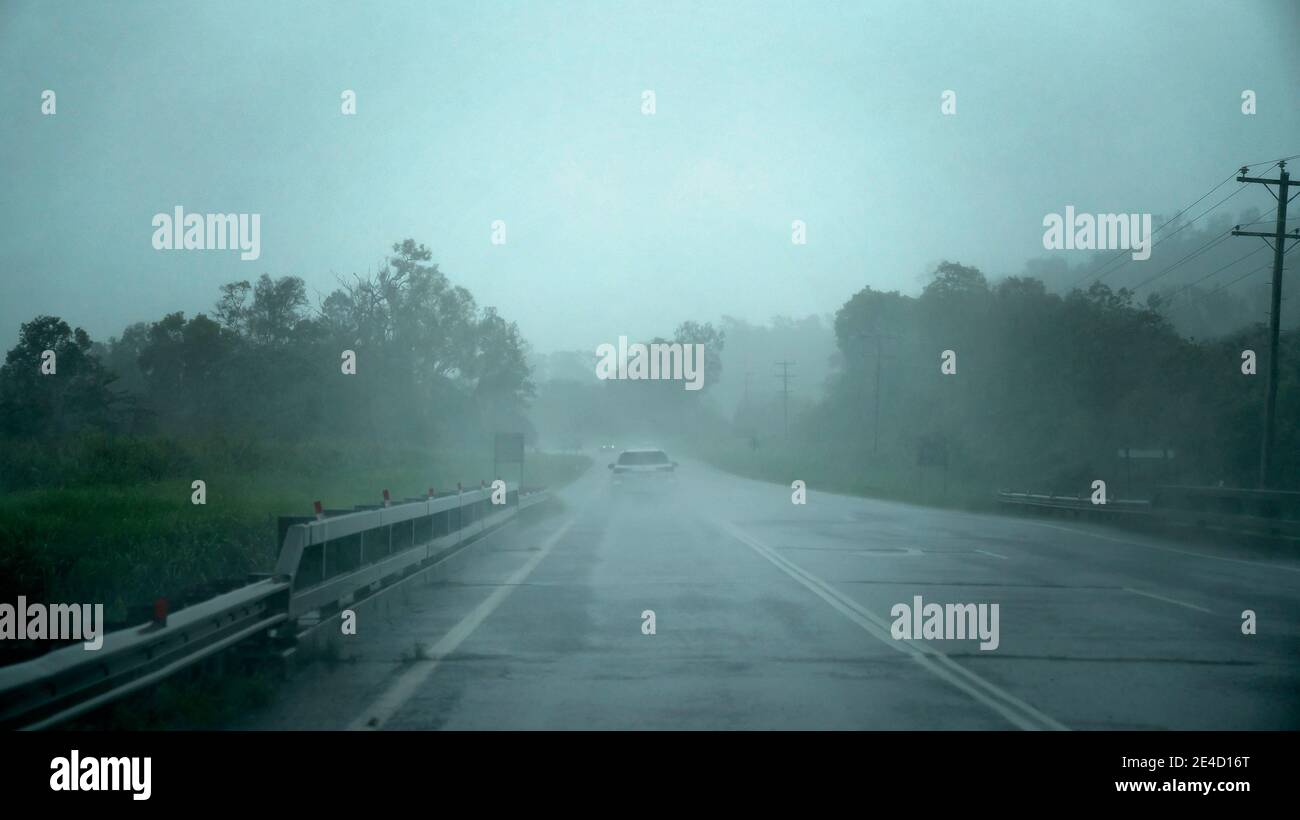 A blurred scene of rain falling on a car windscreen as it travels along ...