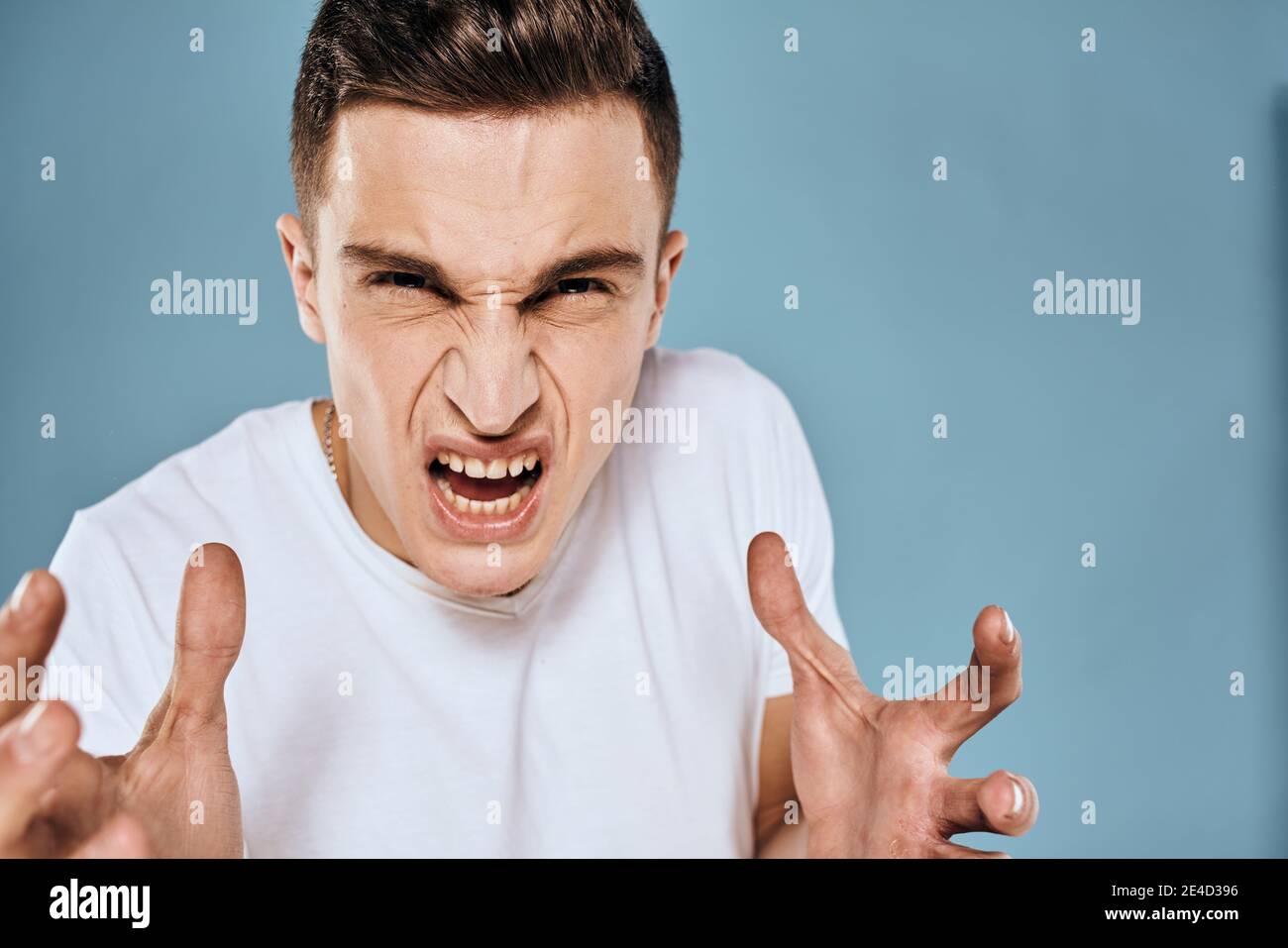 emotional displeased man cropped view white t-shirt blue background ...