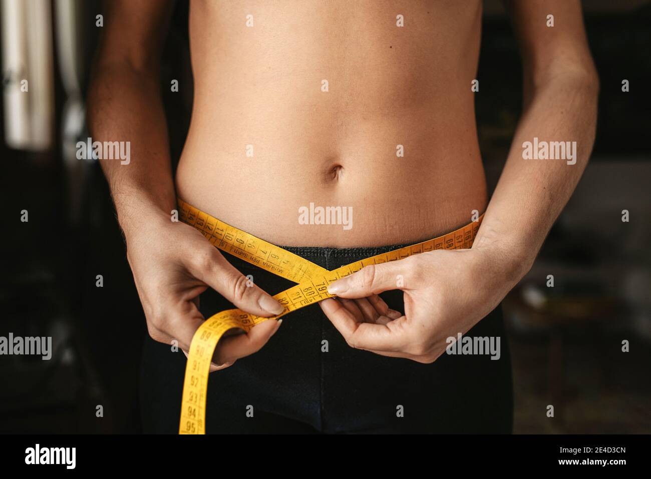 Young female measuring her waist with a measuring tape - the concept of ...