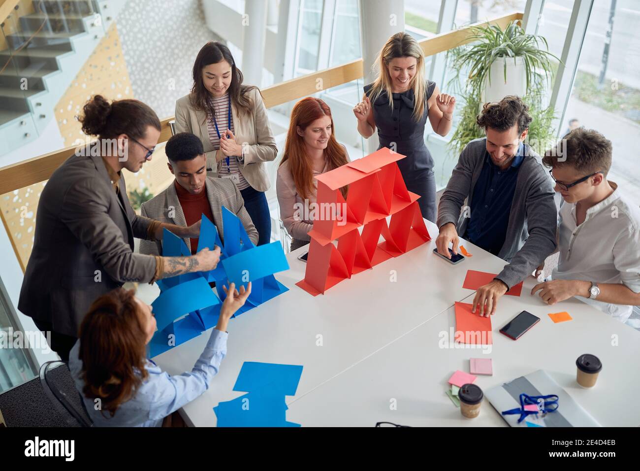 group of young businesspeople playing, building card towers from paper ...
