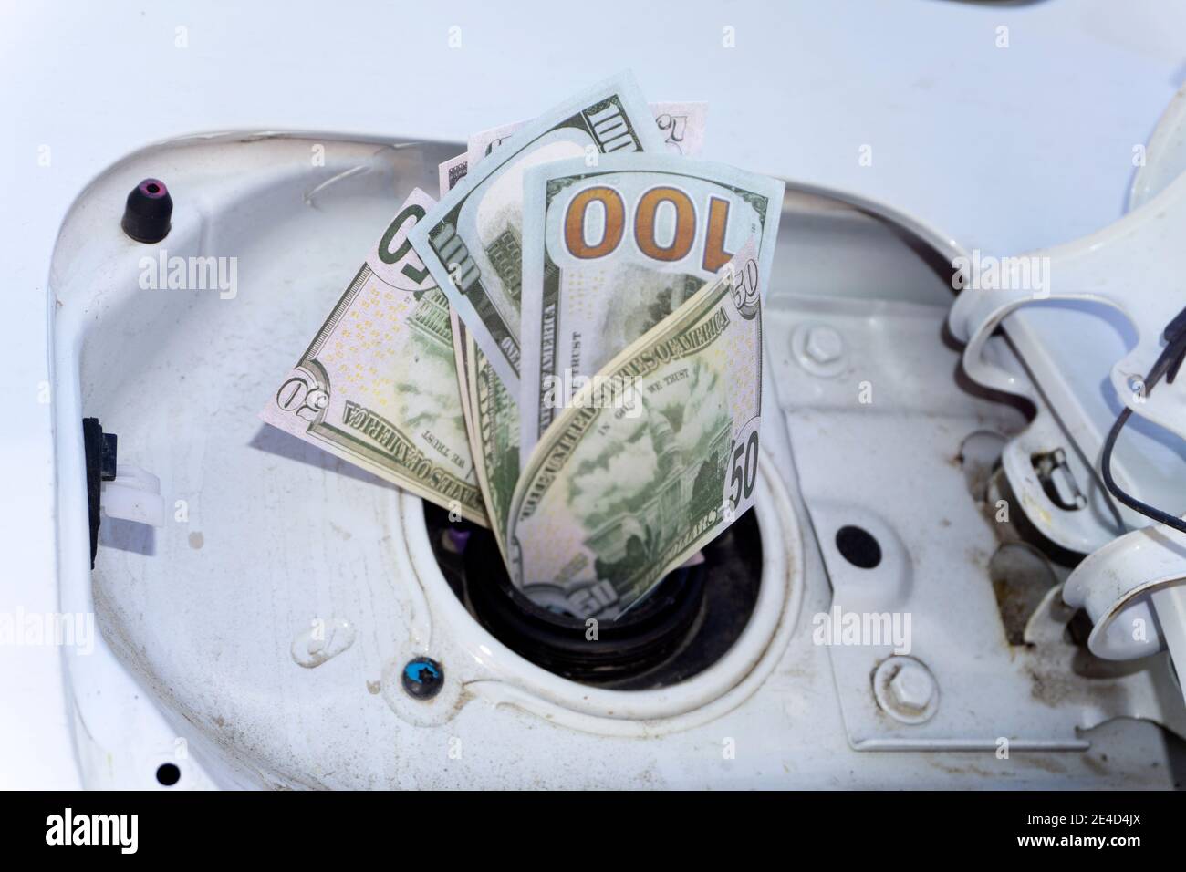 Money sticking out of automobile fuel tank opening signifying and ...