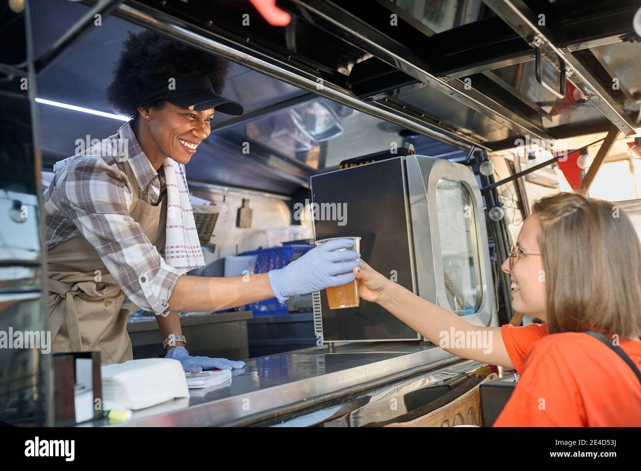 young afro-american female employee in fast food service giving a glass ...