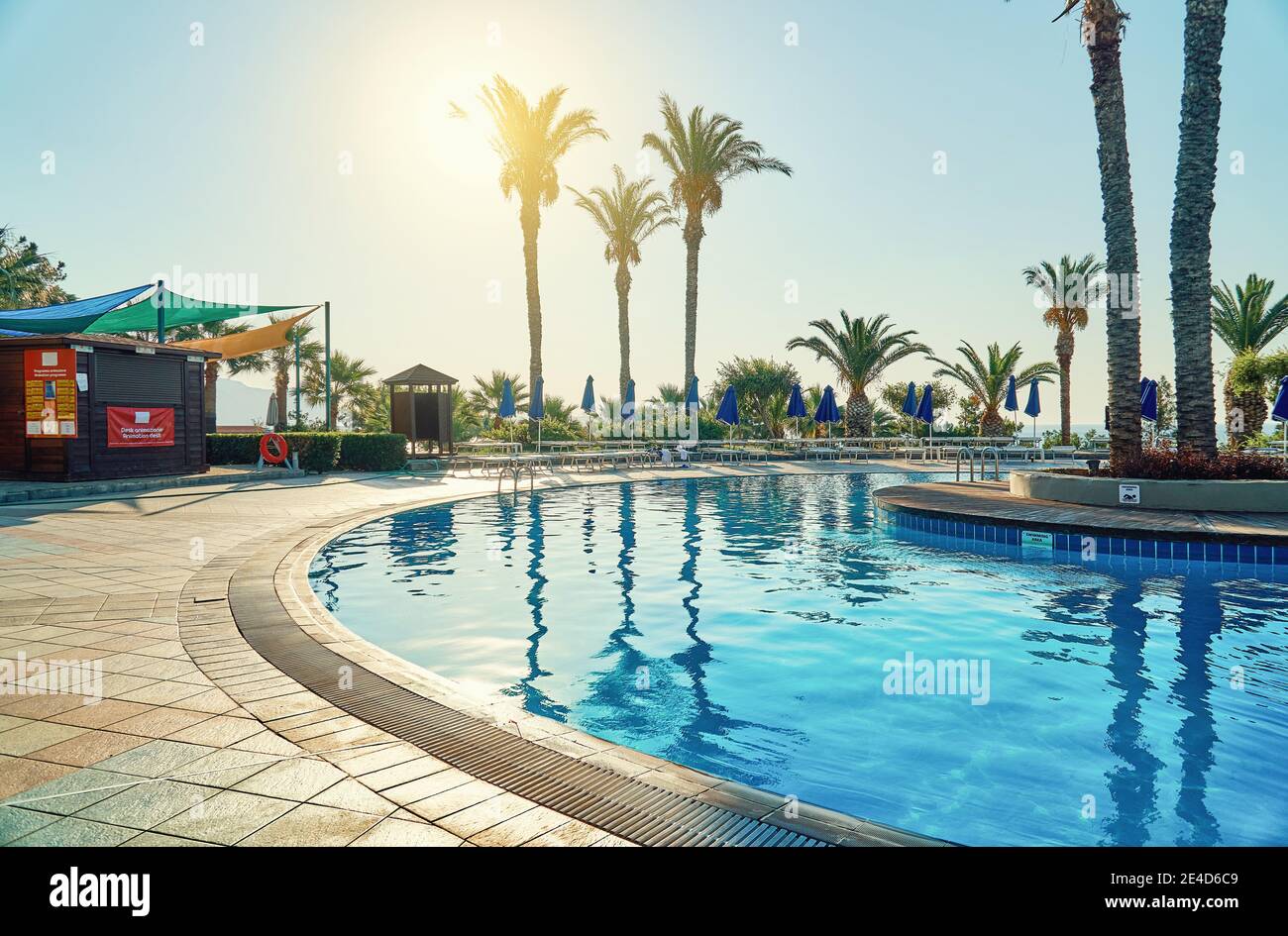 Clean blue pool and tiled poolside of hotel located near palms in sunny ...