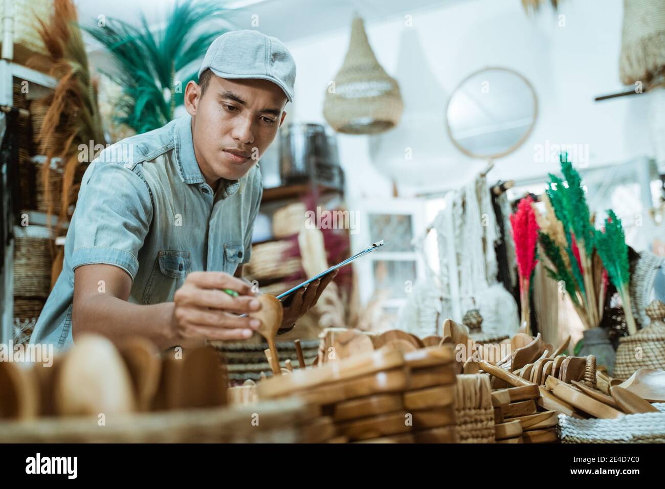 man holds a craft item and clipboard while checking items among craft ...