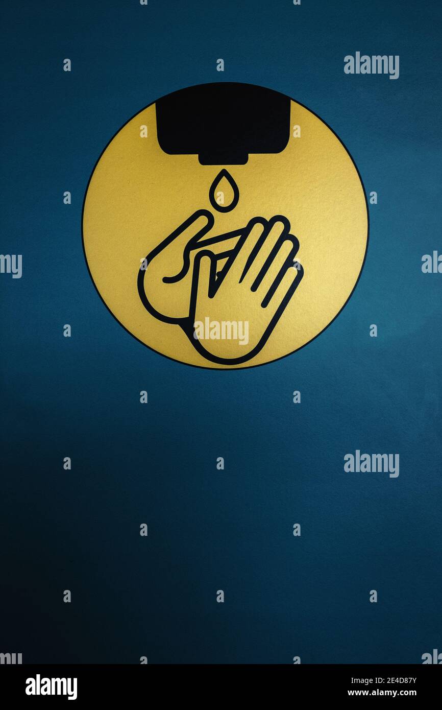 Vertical shot of a yellow sign showing to wash hands Stock Photo - Alamy