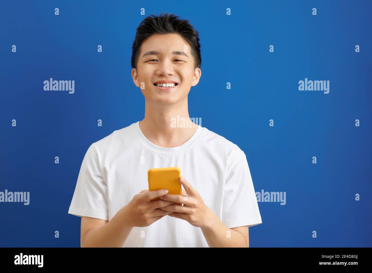 Casually dressed student standing isolated on blue background looking ...