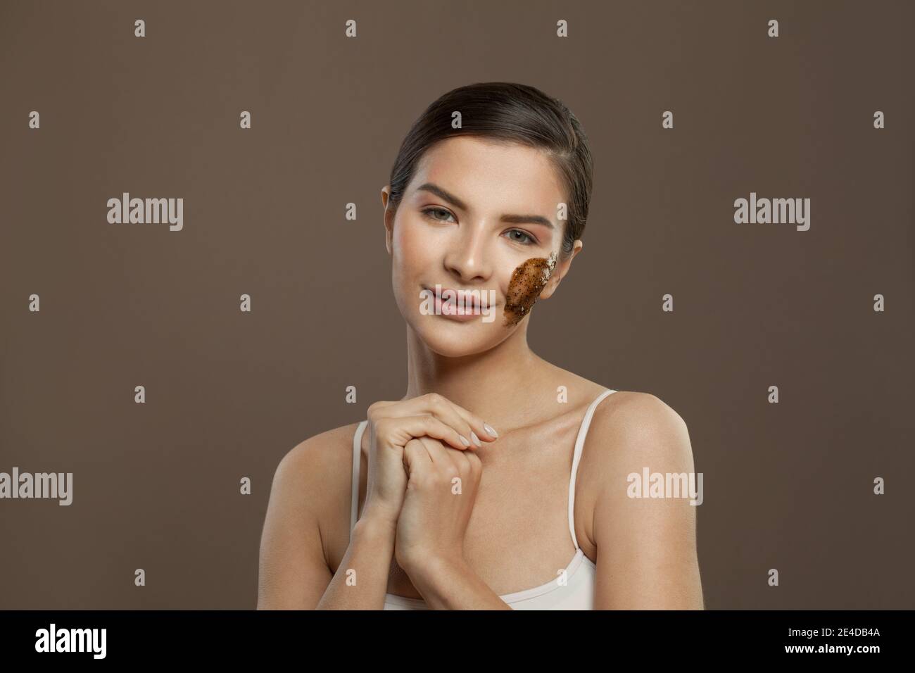 Young woman spa model with brown scrub on her skin. Facial treatment ...
