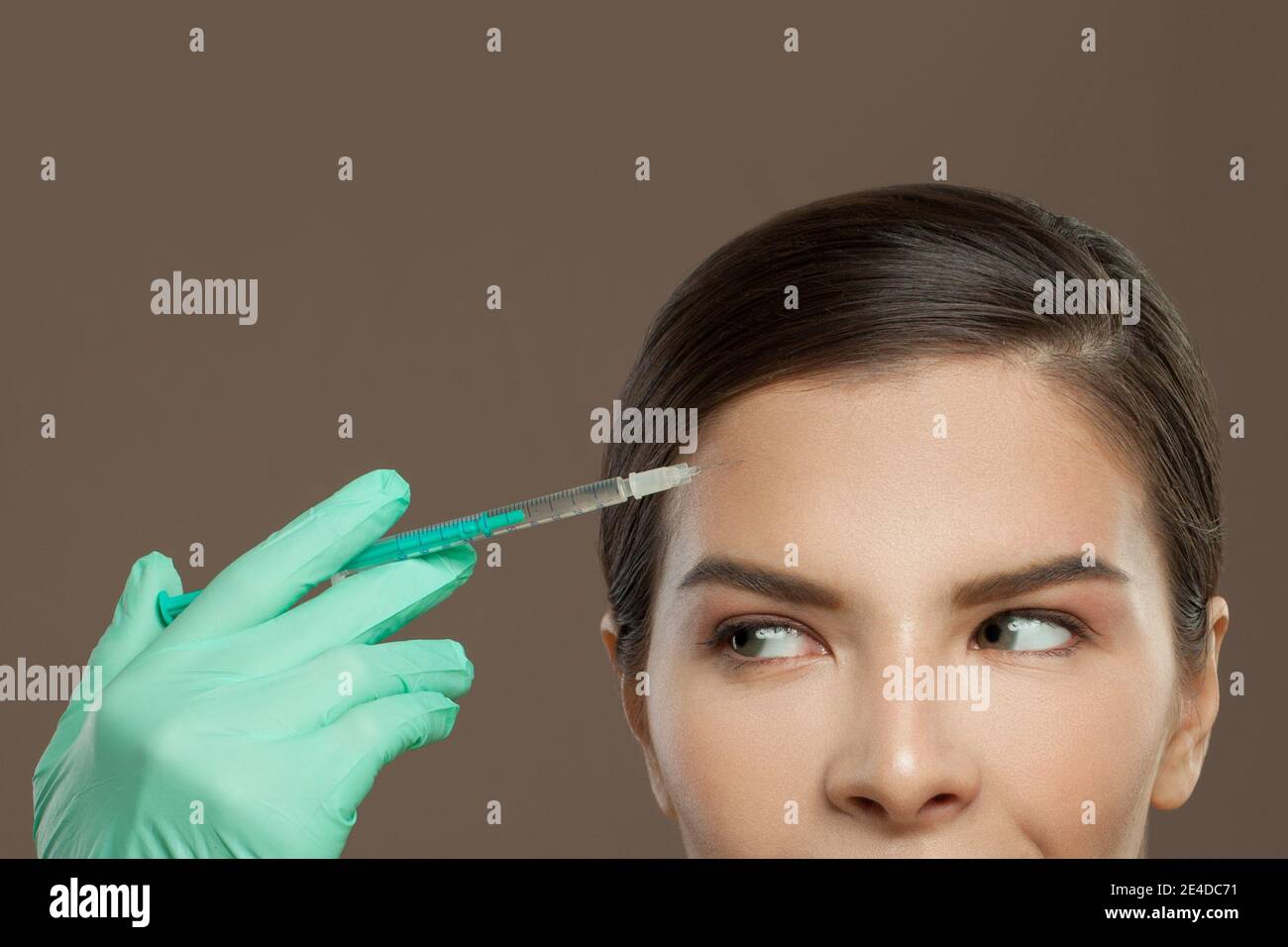 Female forehead and syringe injection closeup. Cosmetology and ...