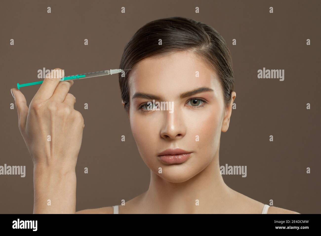 Beautiful woman face with syringe injection on brown background ...