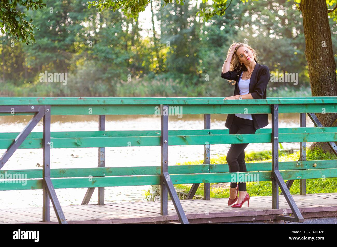 portrait of young attractive woman leaning on a railing of pedestrian ...