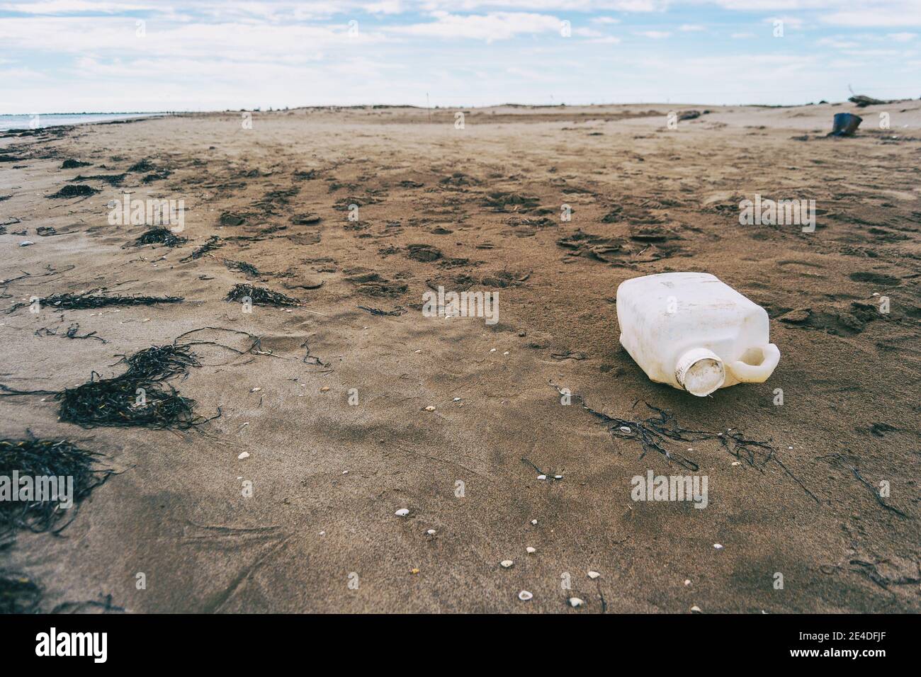 large plastic bottle washed up on a beach. You see the environmental ...
